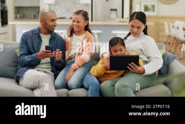 Parents networking with their girl kids on a technology on a sofa in ...