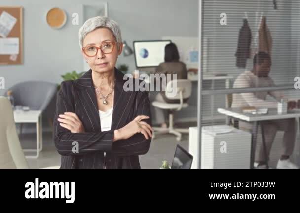 Medium portrait of confident mature Asian lady boss wearing striped ...