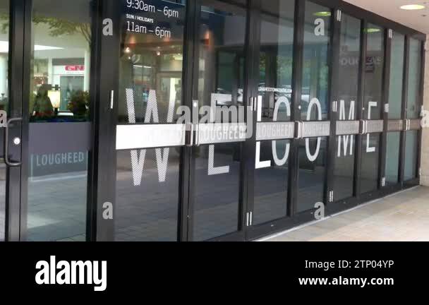 One side of mall entrance with welcome sign on door in Lougheed Town ...