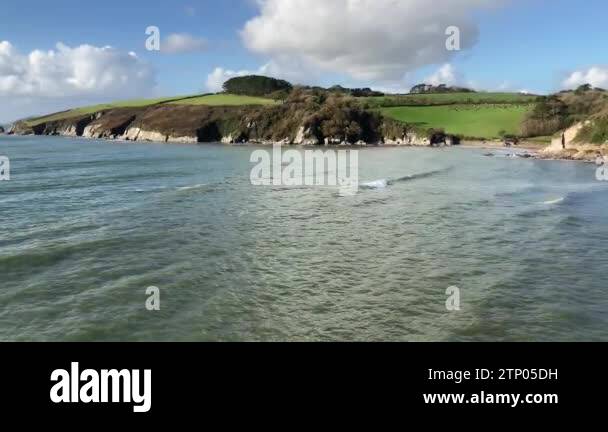 Surfers wait to catch a wave on the Devon coast with the stunning ...