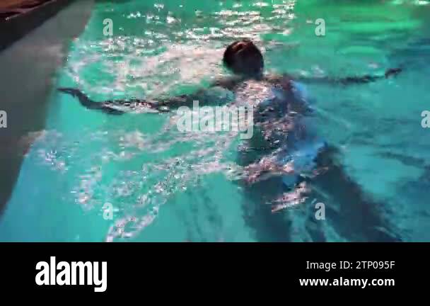 Attractive female model in white swimsuit lying in poolside water at ...