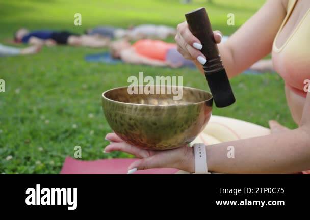 Closeup womans hand playing singing bowls with stick during meditation ...