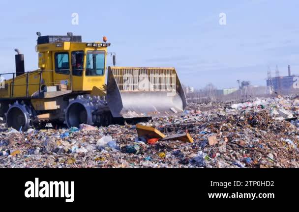 A landfill compactor moves with a raised blade at a city landfill ...