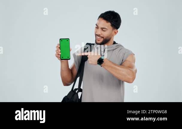 Happy man, personal trainer and pointing to phone green screen, mockup or sign up against a ...