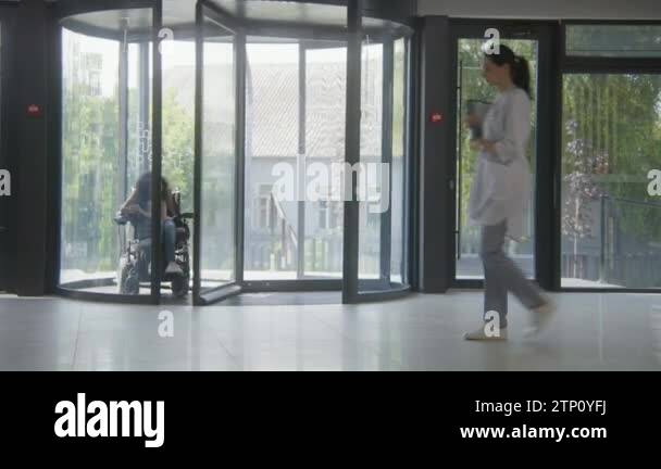 Woman with physical disability rides in clinic entrance on electric ...