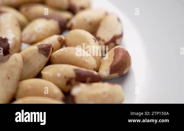 Brazil nuts heap on a white ceramic surface. Vegan, vegetarian ...