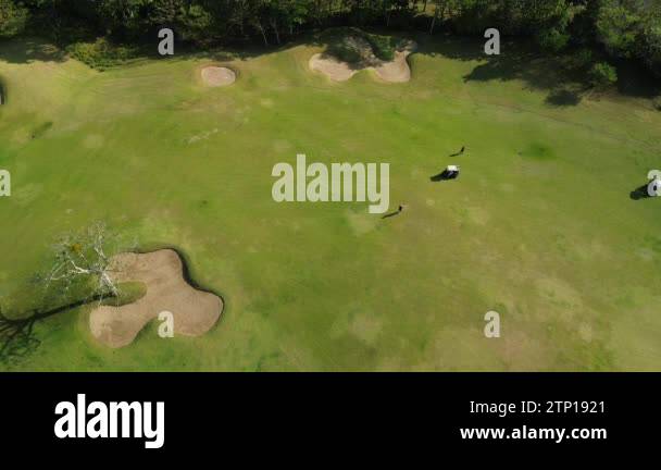 Birds-eye view of golfers moving across green lawns on golf carts ...
