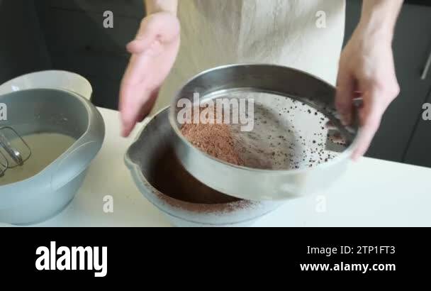 Man sifts cocoa powder through a sieve on the kitchen table. With a ...