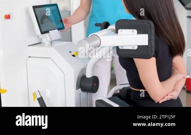 A young girl does back exercises on a modern medical technology machine ...
