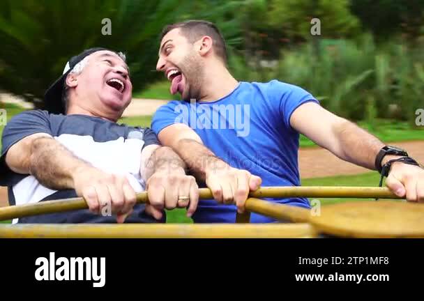 Dad and son playing on roundabout Stock Video Footage - Alamy