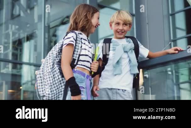Two school children pupils girl and boy classmates friends standing on ...