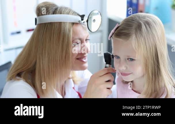 Ent with frontal reflector examining little girl ear using otoscope 4k ...