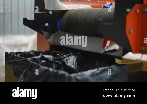 Close-up candy wrappers falling down from conveyor belt in garbage bins ...