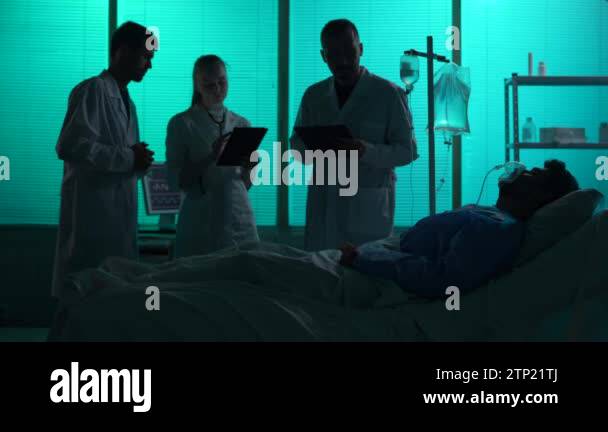 Full-sized silhouette video of three doctors standing around a patient ...