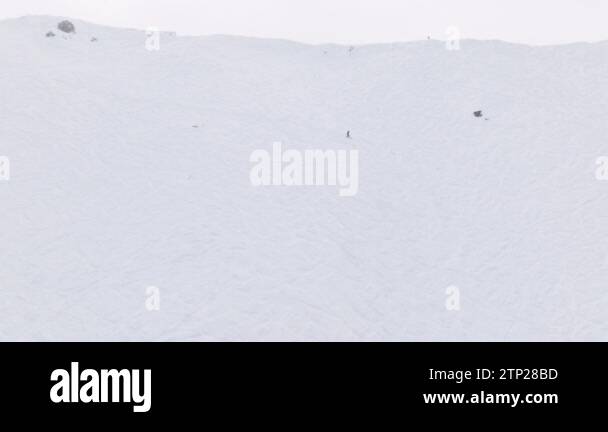 Skiers riding down with high speed on steep slope in glacier ski resort ...