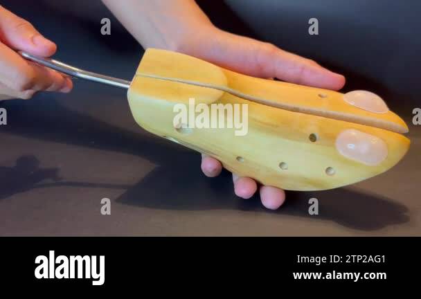 Skilled hands use shoe stretcher, highlighting features and size ...