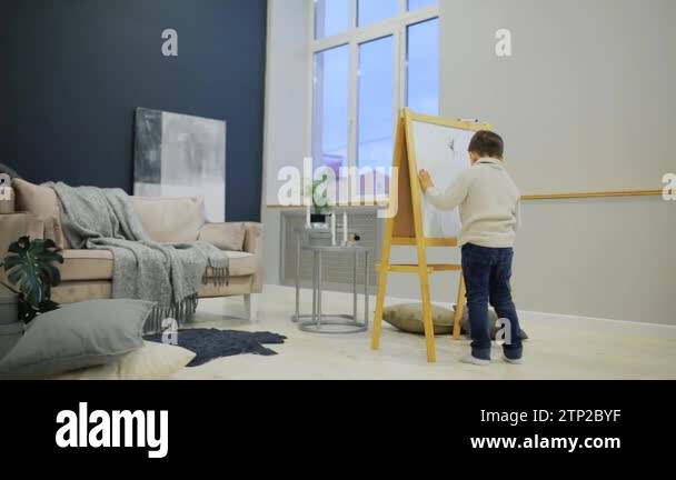 The little boy in the living room of the house draw on the Board with ...