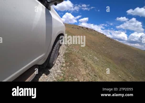 Drive an SUV through the hills of the mountains. A white car drives ...
