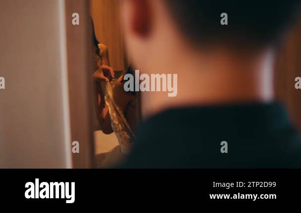 an Asian man is spying on his girlfriend while in the bathroom of a hotel room at night Stock ...