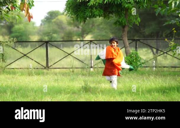 Cute little indian boy running with Indian Tricolour flag on greenery ...