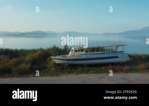 Drone view of old abandoned pleasure or fishing boat on shore of lake ...