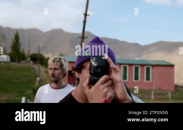 A young hipster man captures moments with an air of nostalgia, photographing with a vintage ...