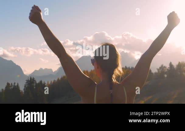 CLOSE UP, LENS FLARE: Triumphant moment of a lady reaching scenic ...