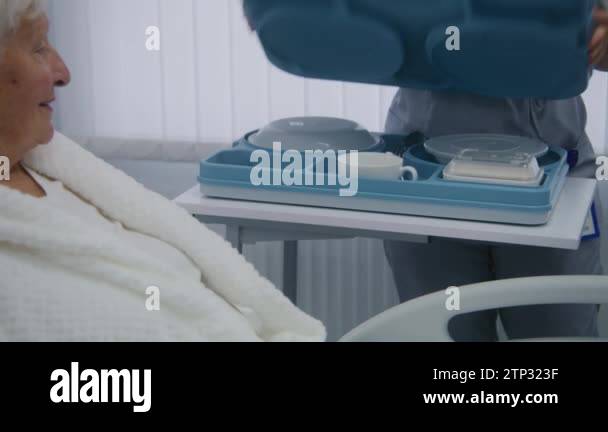 Nurse opens lunch box with delicious food to female elderly patient ...