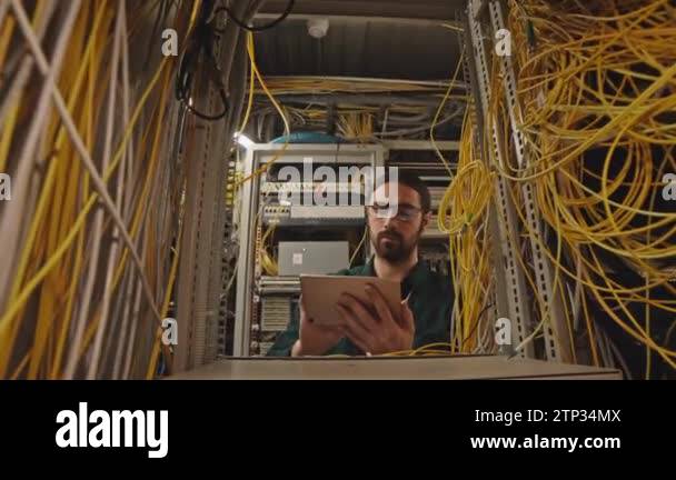 Male system administrator using tablet PC while fixing and connecting ...