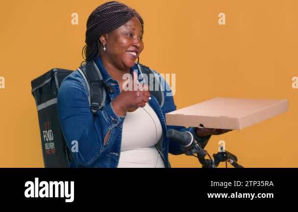 Black woman on bicycle brings package from restaurant for timely and ...