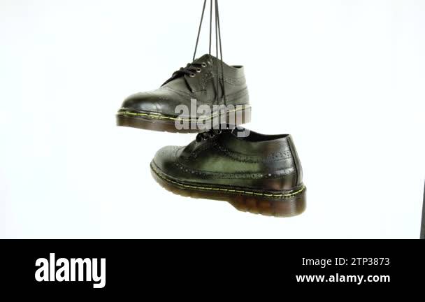 Full black wingtip brogue shoes with rubber sole hanging by laces on a ...