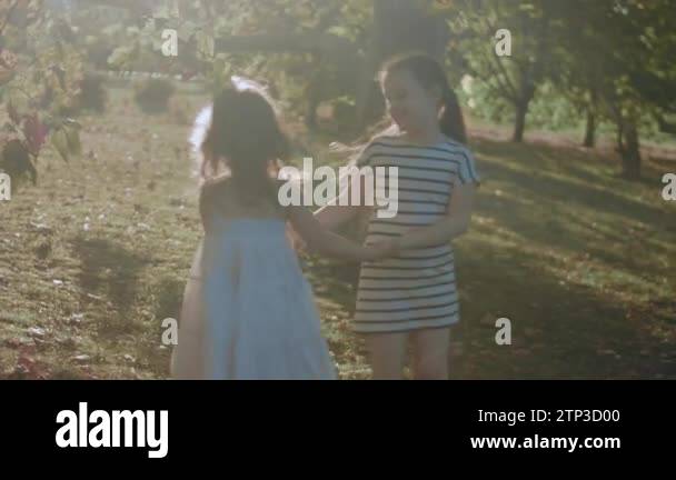 Two curly girls having fun to play together in the park. Two beautiful ...