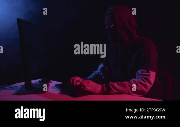 Spy hacking computer sitting in a dark room. Black smoke background ...