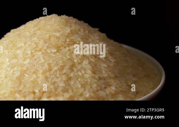 Dry Uncooked Parboiled Rice Heap Rotating against Black Background. A ...