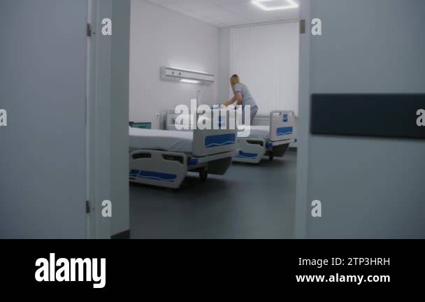 Adult nurse in gloves wipes bed and patient bedside panel with rug in ...