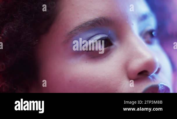 Biracial woman with dark curly hair in blue and pink light, slow motion ...
