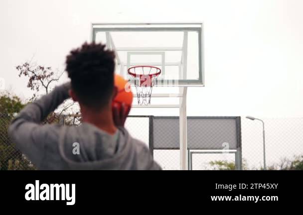Young african player jumping up and throwing ball in a basketball hoop ...