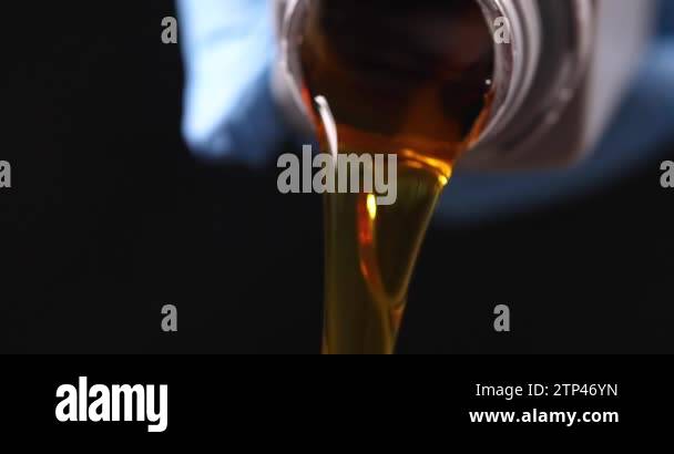 Clear yellow oil is poured from plastic bottle. Car engine oil drop ...