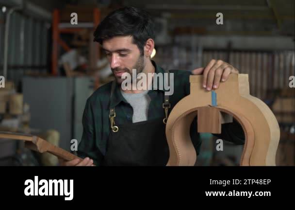 A skilled luthier is hard at work sanding the body of an acoustic ...
