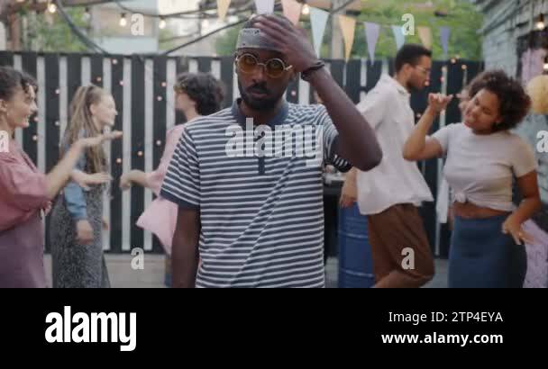 Portrait of unhappy African American man standing at open air party ...