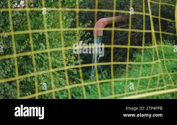 Water Pollution. View through fence, rusty pipe, discharge of polluted ...