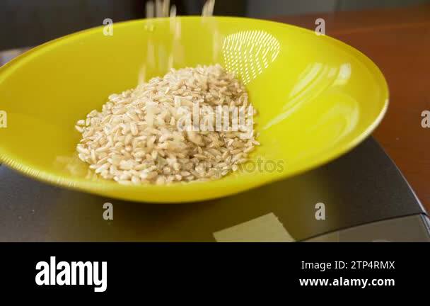 someone measures a piece of brown rice, on an electronic scale in the ...