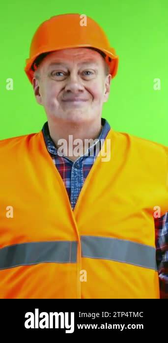 Senior friendly builder in hardhat waves palm for greeting or goodbye ...