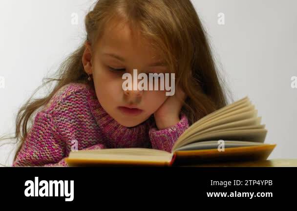 Young girl smiling while reading book. Front view of cute teen lying ...