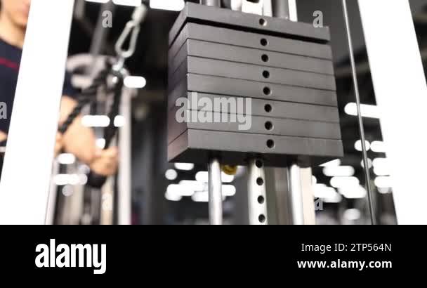 Man lifts weights on machine in gym. Heavy black iron plates stacked ...