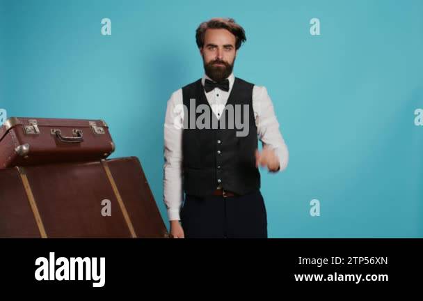 Bellboy raises hand to show stop sign against blue background, working ...