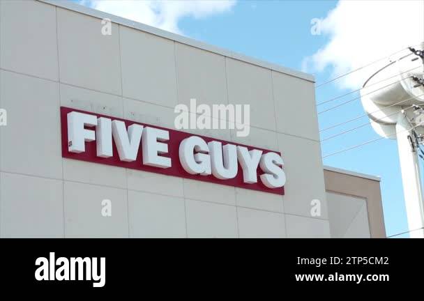 five guys logo writing caption text on storefront restaurant wall next ...