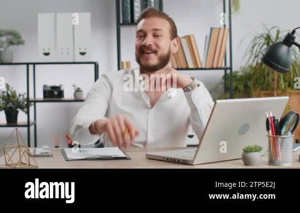 Hello. Lebanese business man working on laptop computer smiling friendly at camera and waving ...