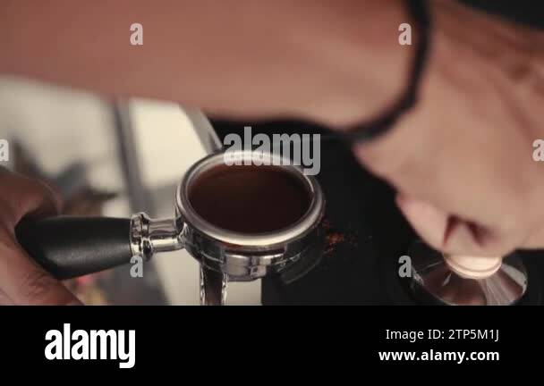 Close-up professional grinding and manual pour to holder freshly roasted coffee for espresso ...