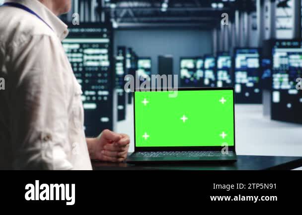 Programmer in server room expertly managing data while navigating through industrial rackmounts ...
